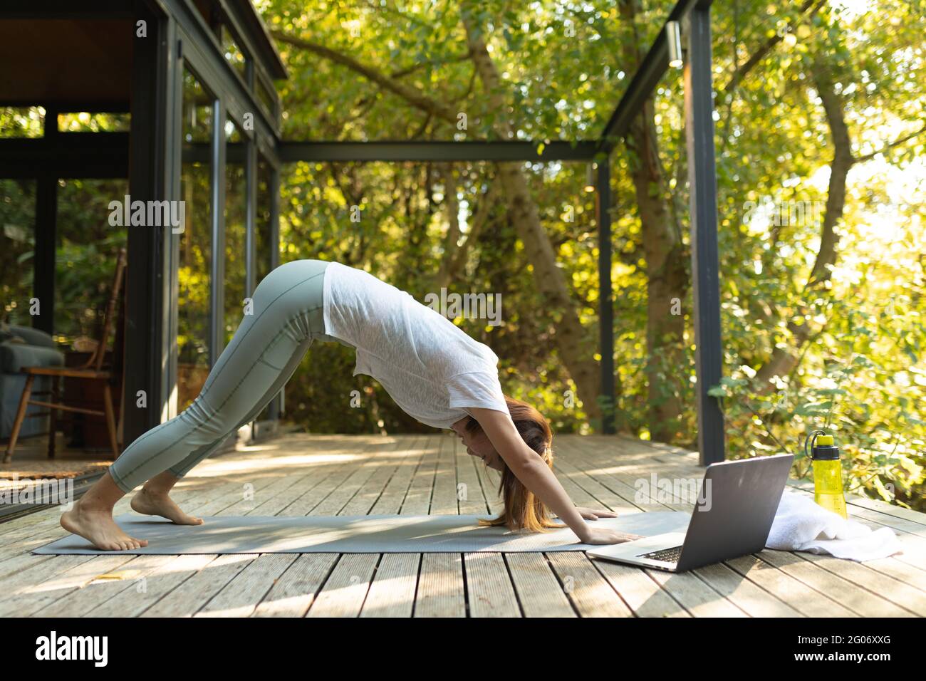 Asian woman practicing yoga using laptop on terrace in garden Stock ...