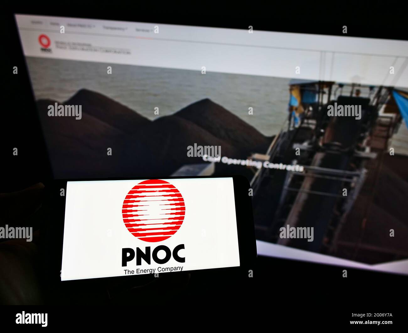 Person holding smartphone with business logo of Philippine National Oil ...