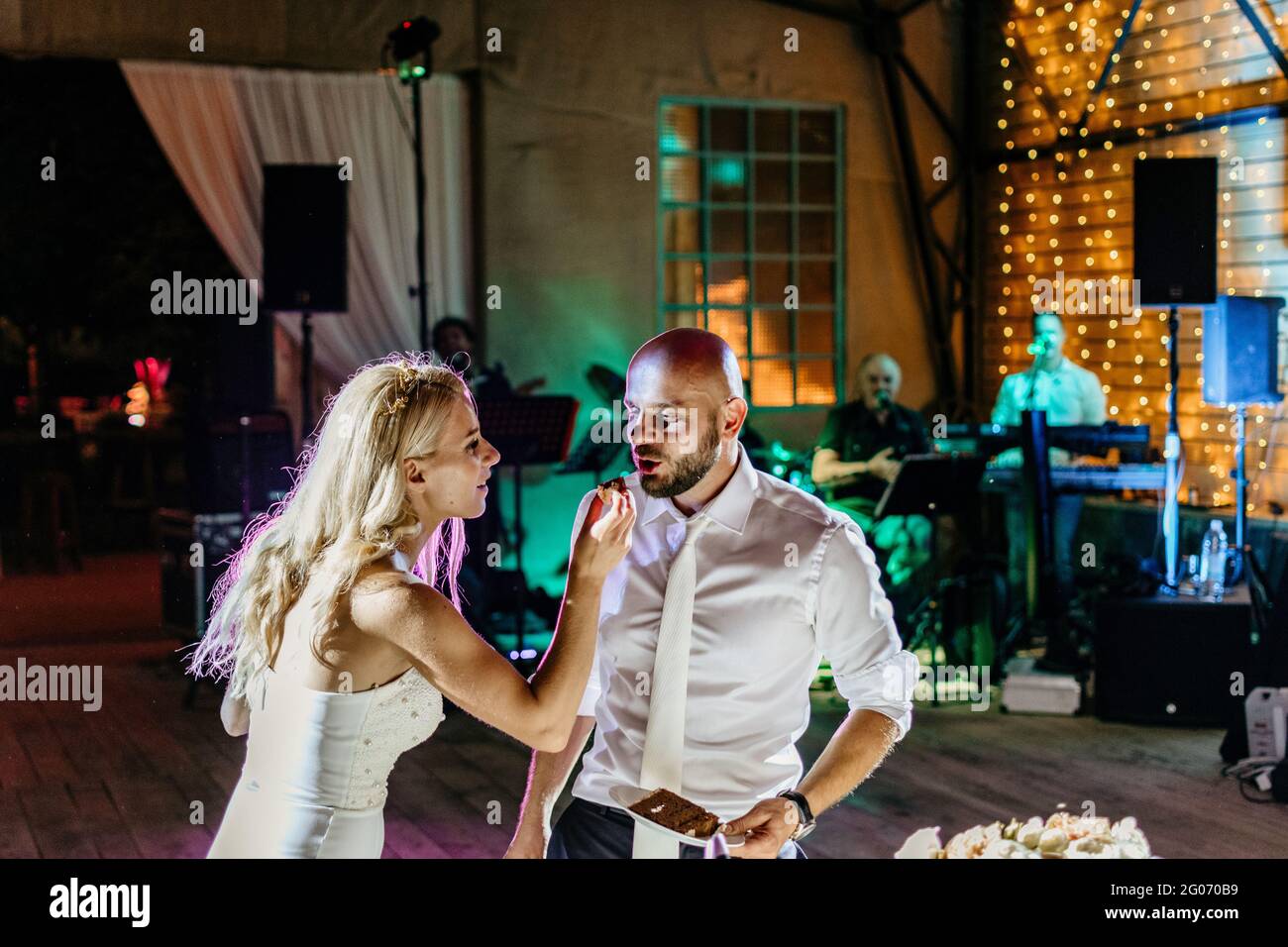 Bride and groom eating and feeding each other cake at wedding reception ...