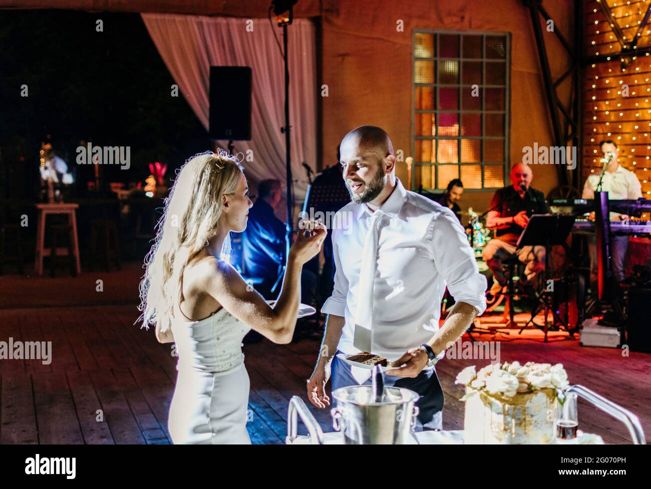 Bride and groom eating and feeding each other cake at wedding reception ...