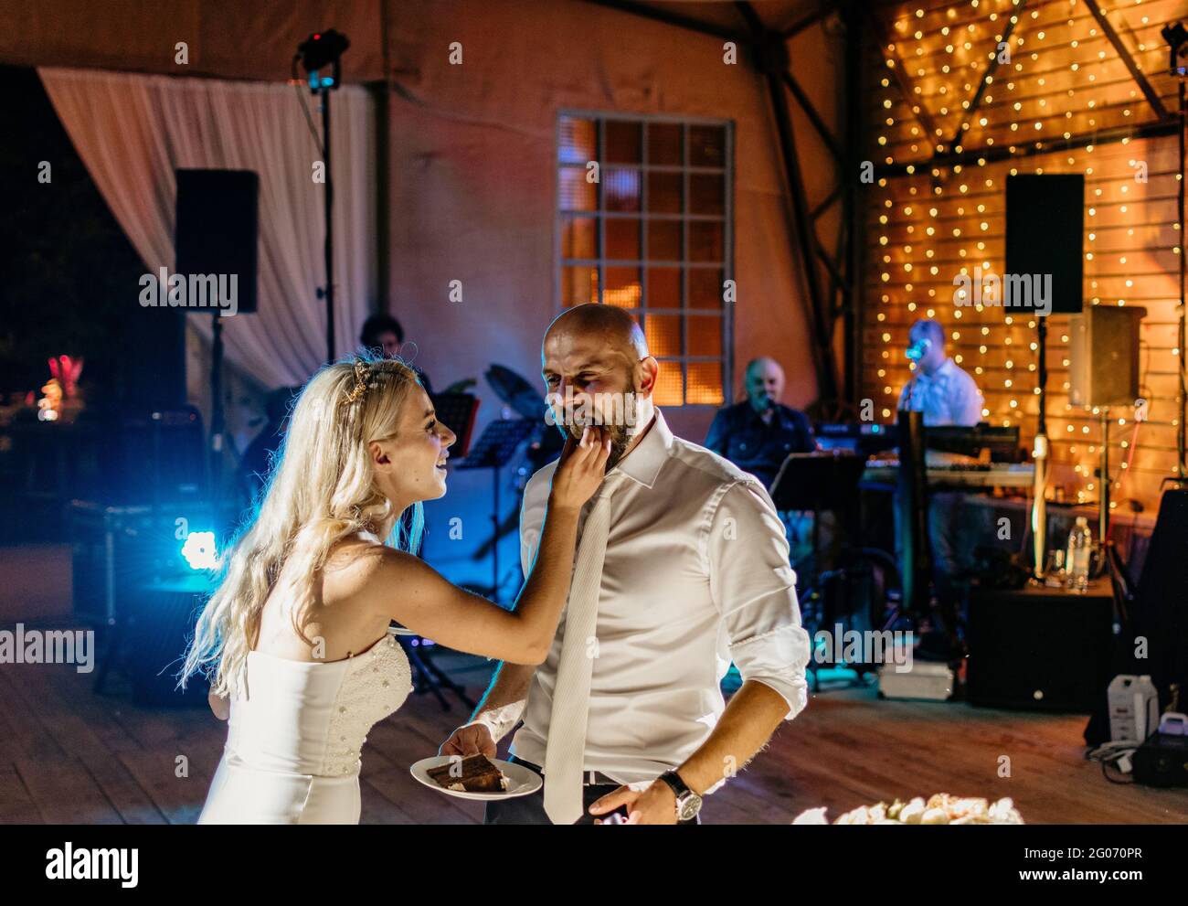 Bride and groom eating and feeding each other cake at wedding reception ...