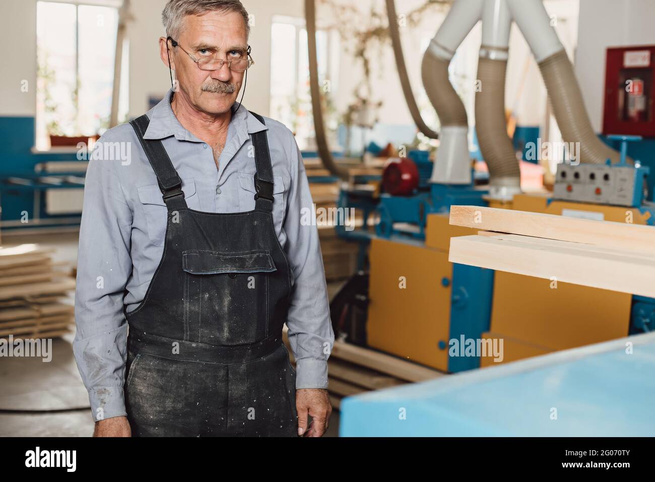 Portrait of an elderly carpenter or carpenter in overalls working with ...