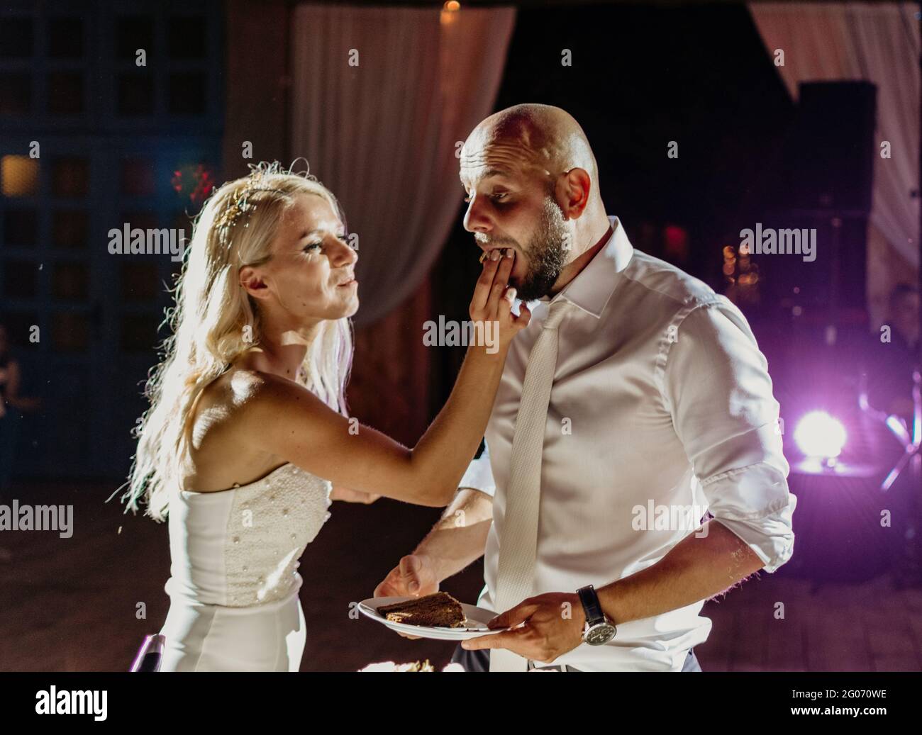 Bride and groom eating and feeding each other cake at wedding reception ...