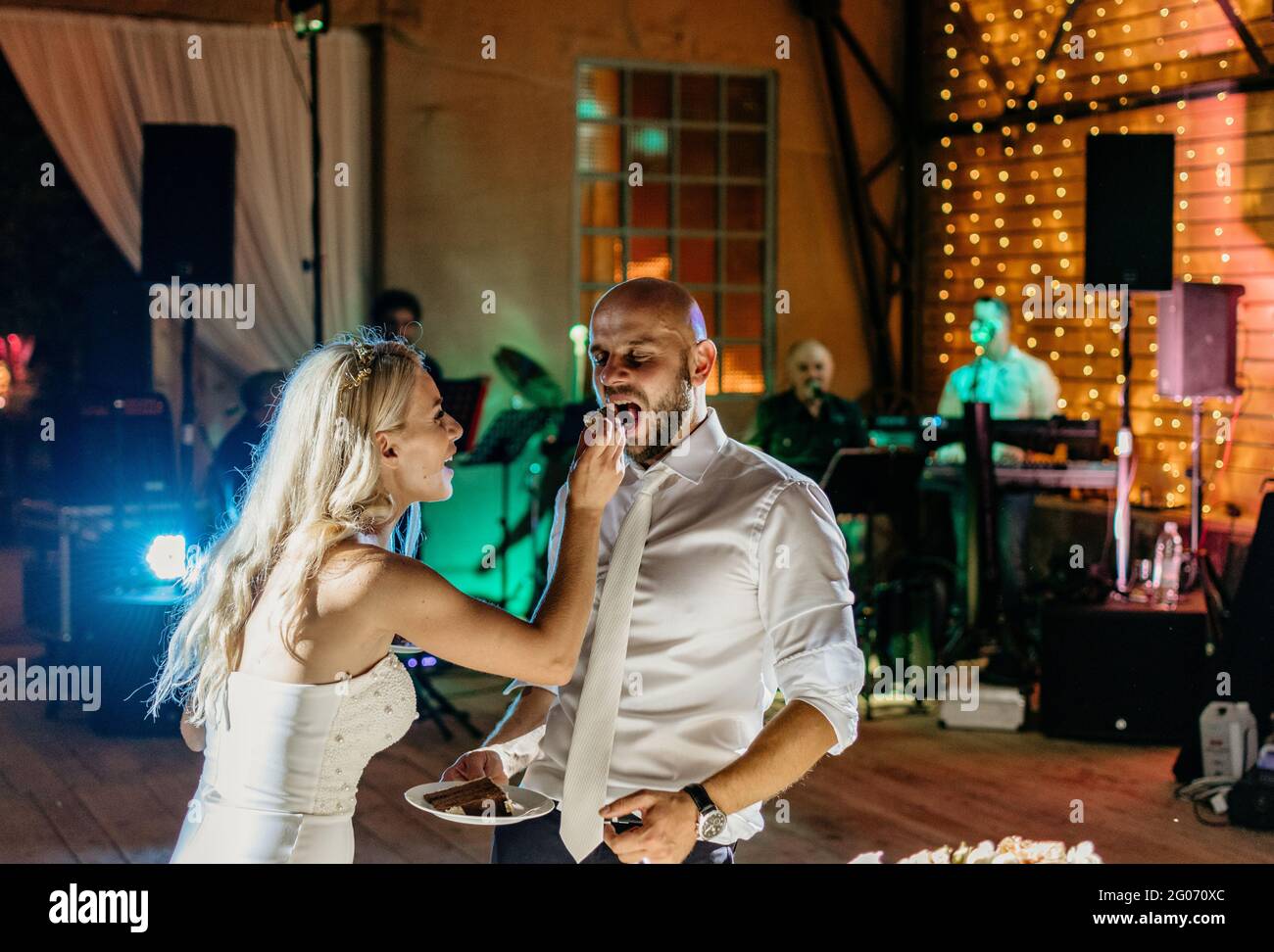Bride and groom eating and feeding each other cake at wedding reception ...