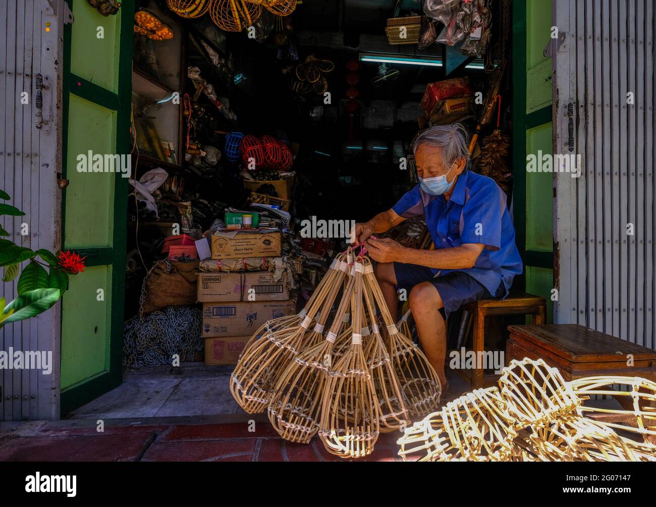 An elderly male worker bundles up some bamboo made products outside the ...