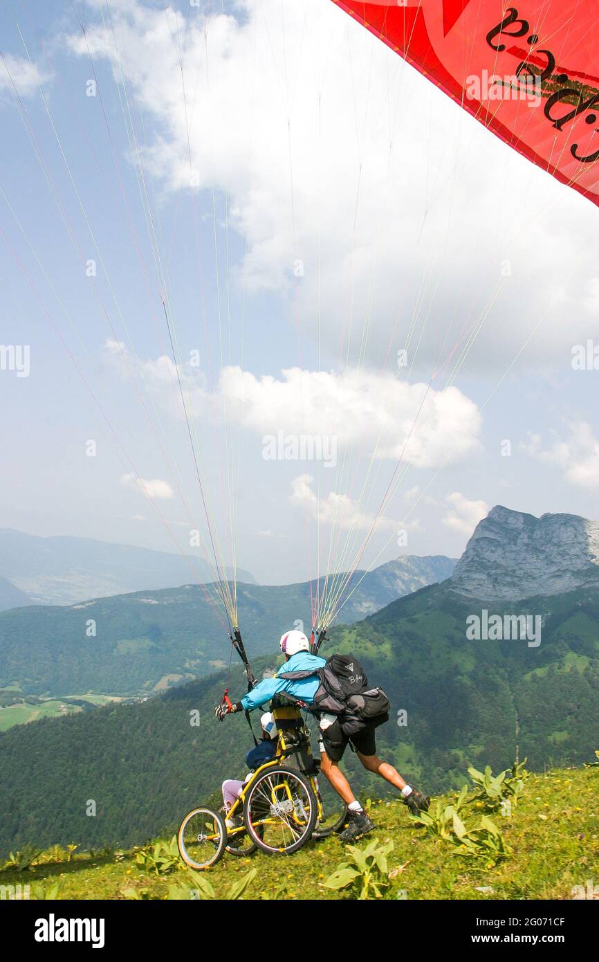 A young disabled child practices paraglider, seated in a special ...