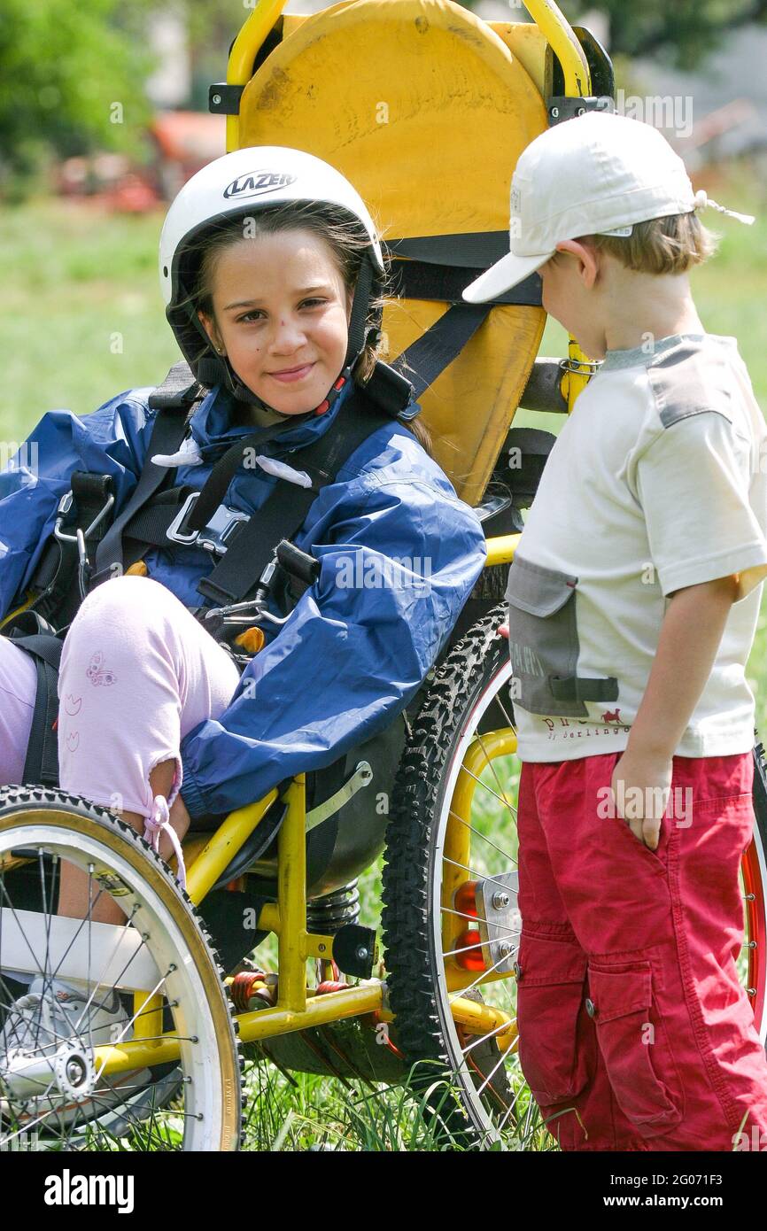 A young disabled child practices paraglider, seated in a special ...