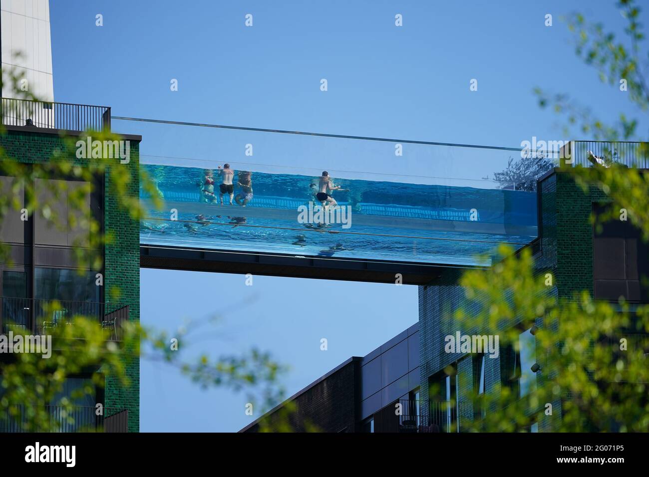 People swim in the Sky Pool, a transparent swimming pool bridge across ...