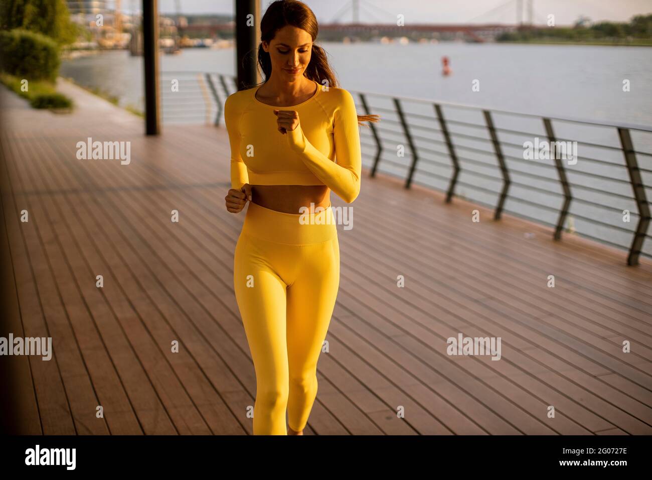 Pretty young woman taking running exercise by the river promenade Stock ...