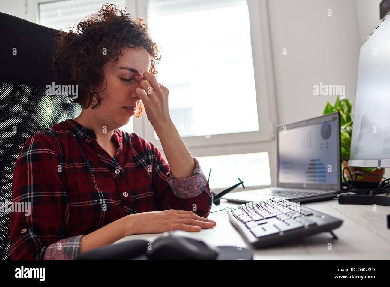 Woman tired of working in front of the computer rests her head on her ...