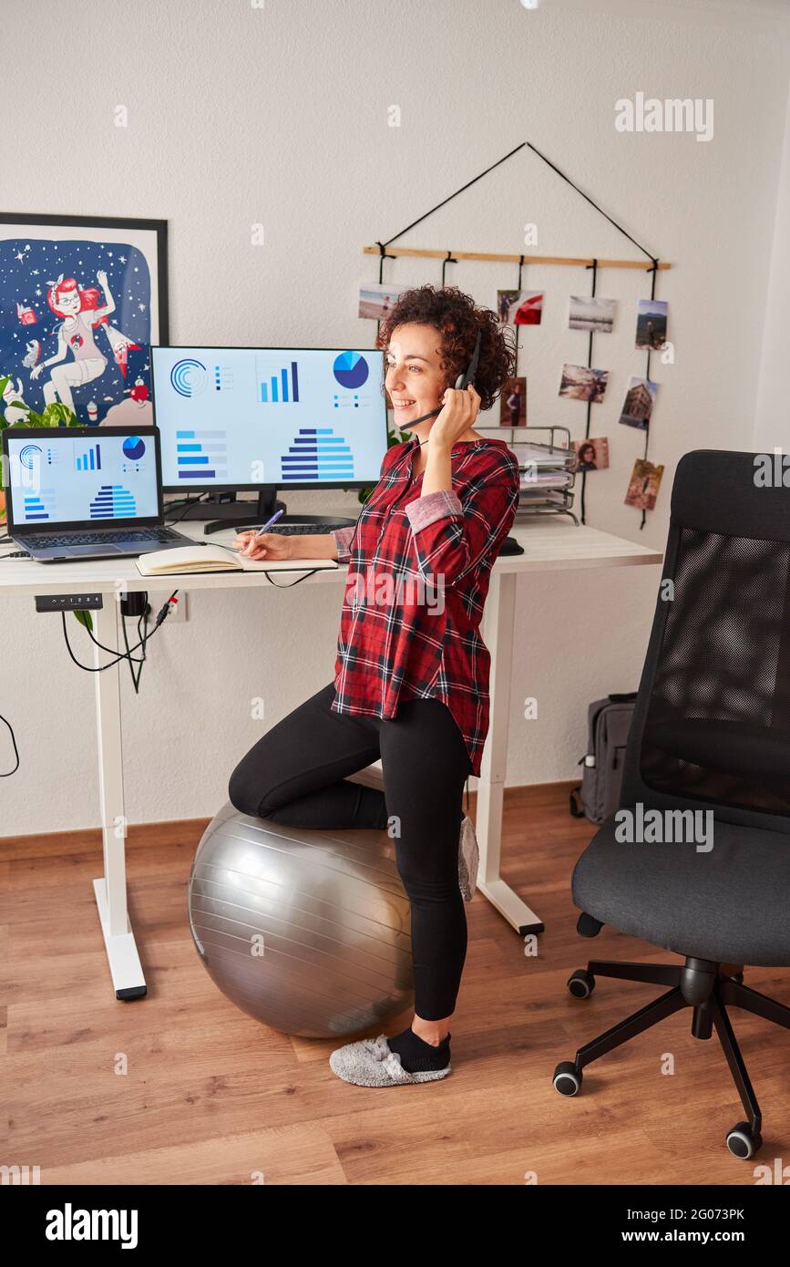 Woman working standing from home with an adjustable height desk and ...
