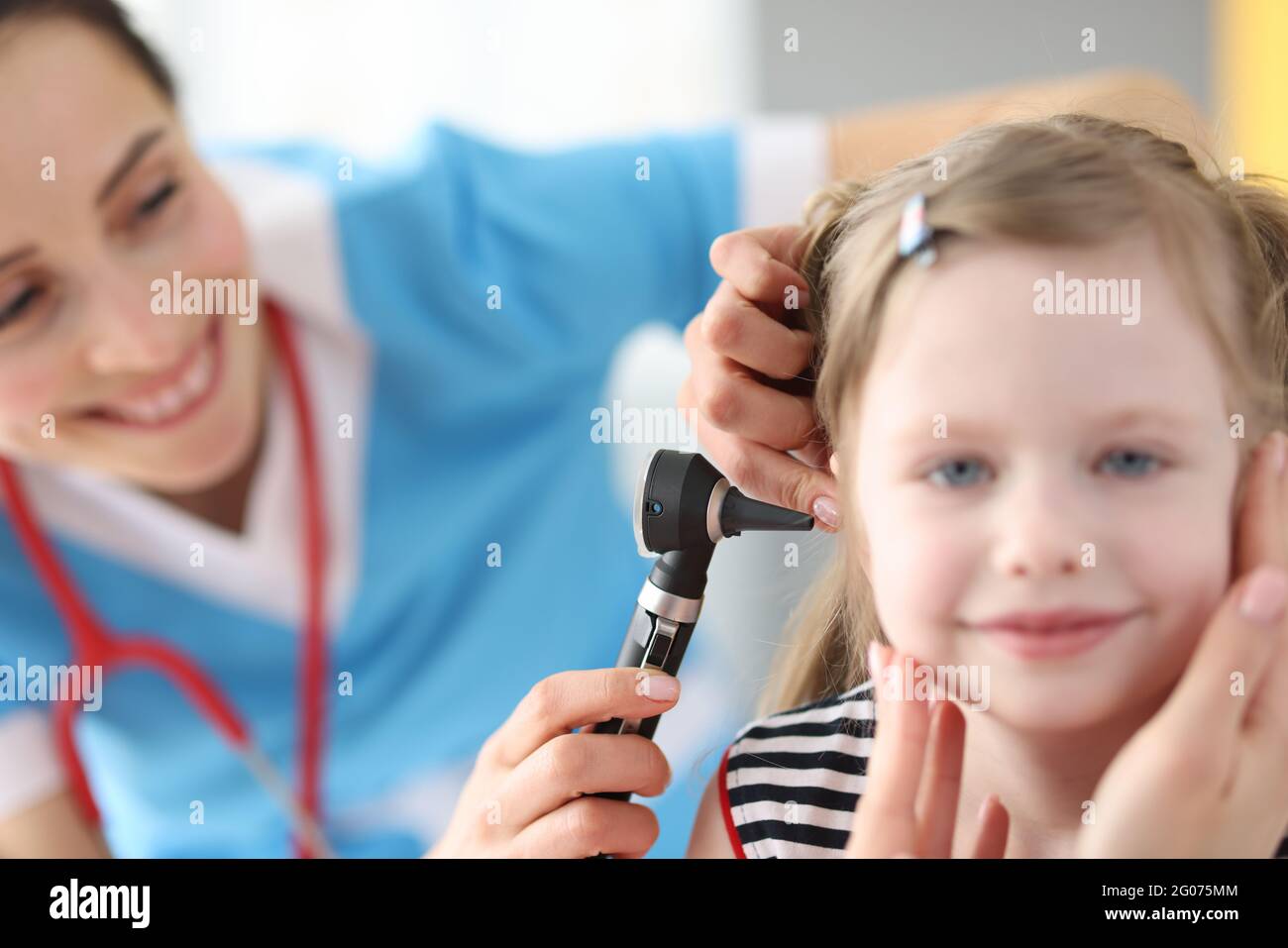 Female doctor conducts medical examination of ear with an otoscope to ...