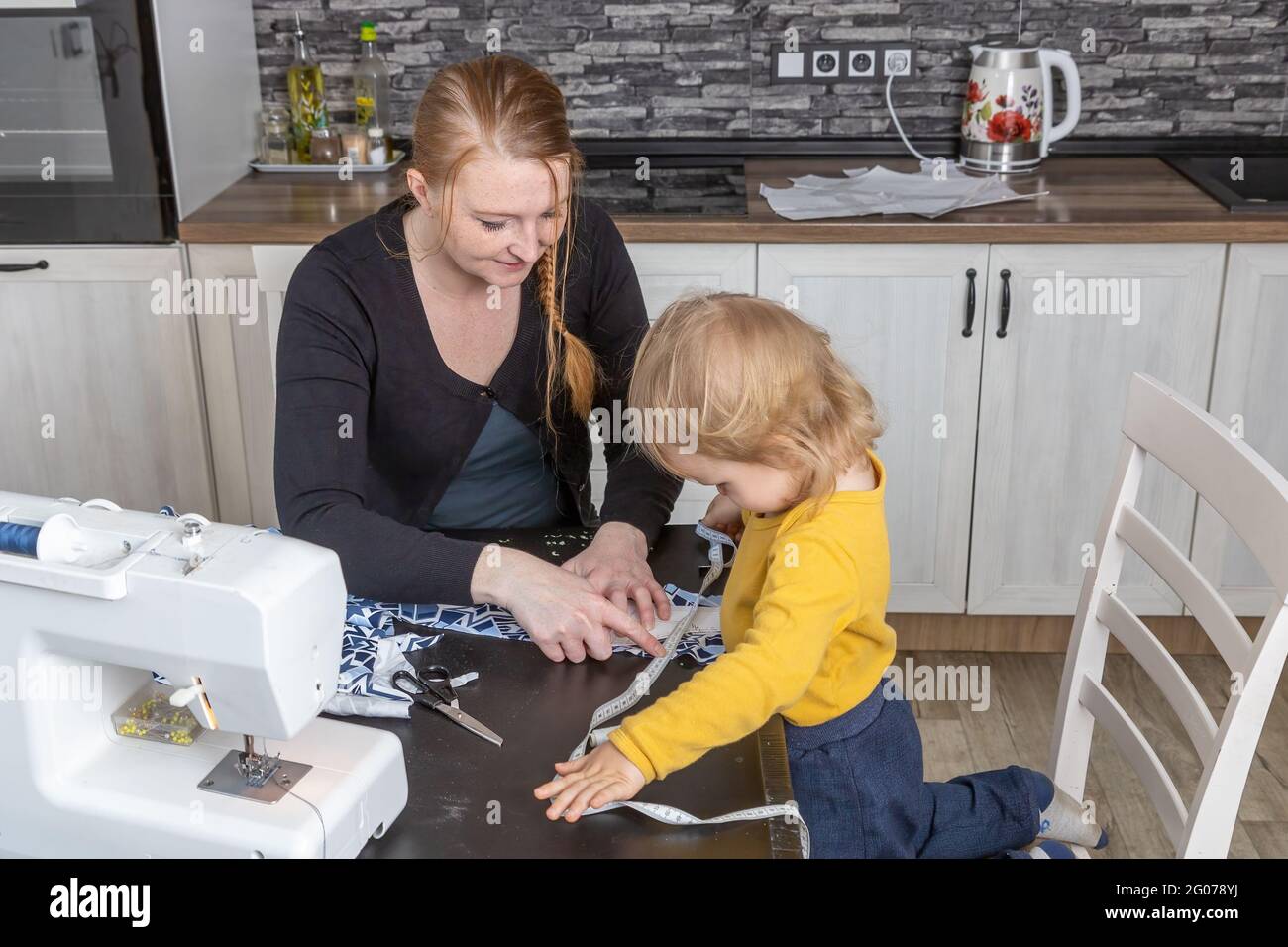 Young mother is sewing with her little son together. Horizontally Stock ...