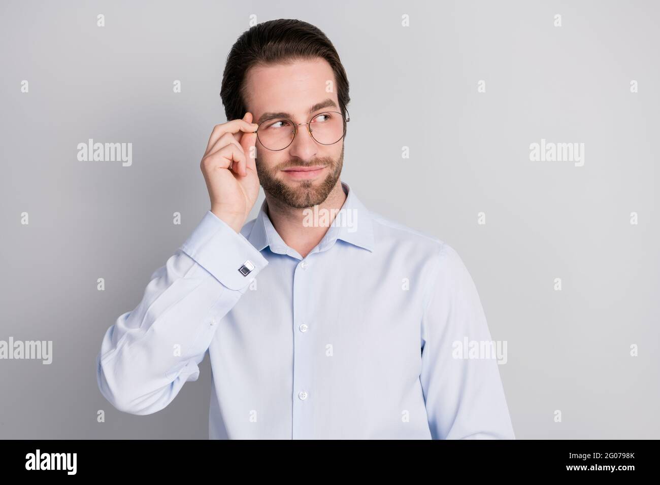 Portrait of attractive imposing man expert touching specs looking aside ...