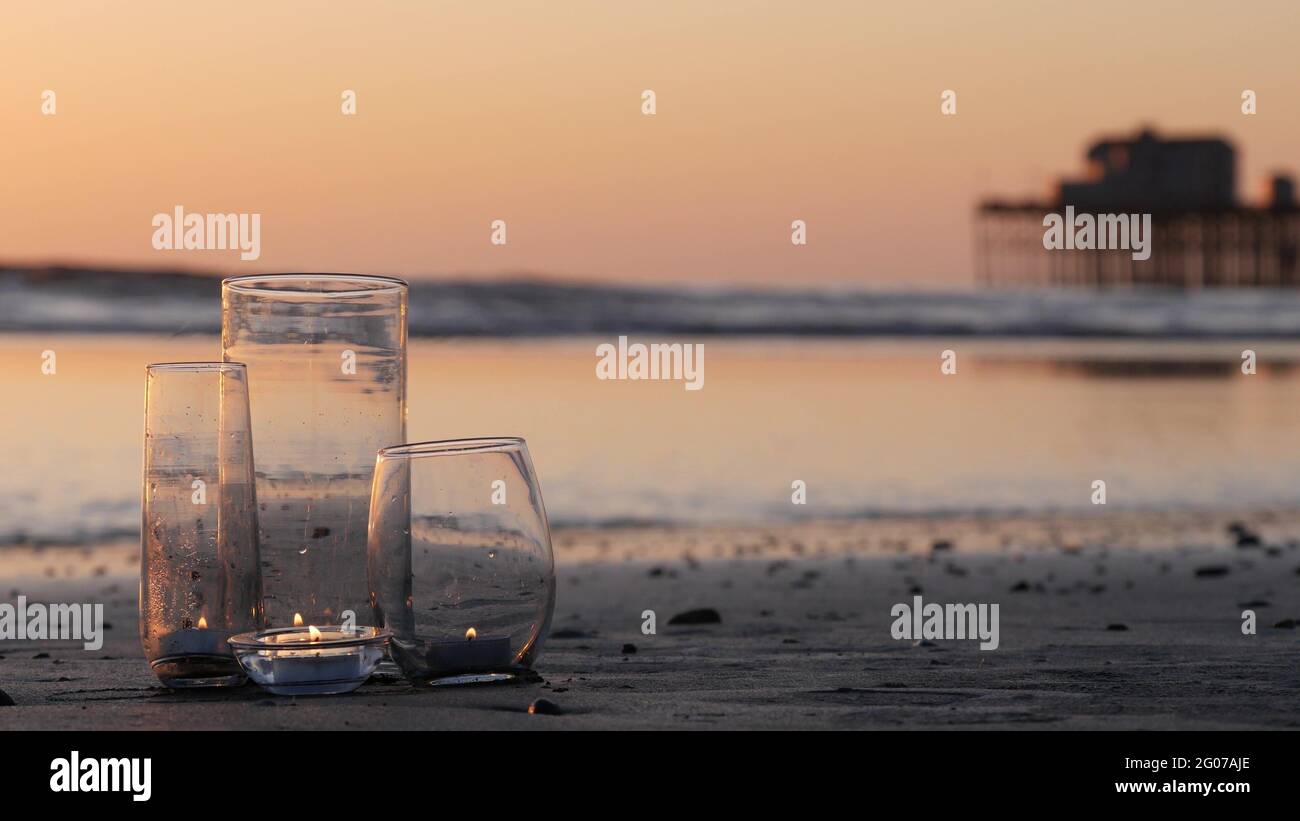 Candle flame lights in glass, romantic beach date by California ocean ...