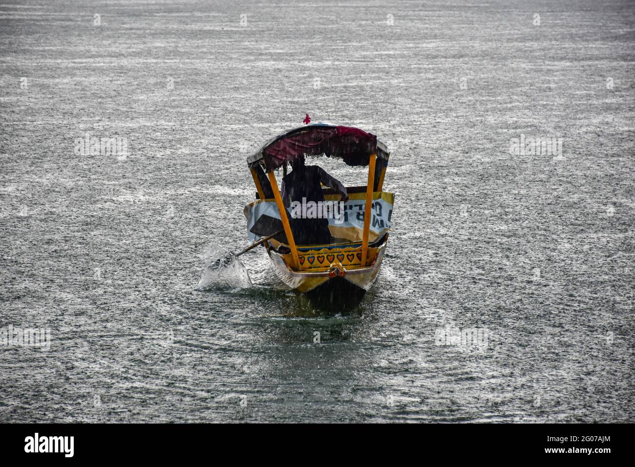 A man rows his boat along Dal lake during rainfall in Srinagar. (Photo ...