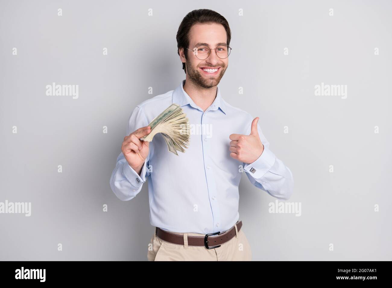 Portrait of handsome trendy cheerful man holding in bunch money showing ...