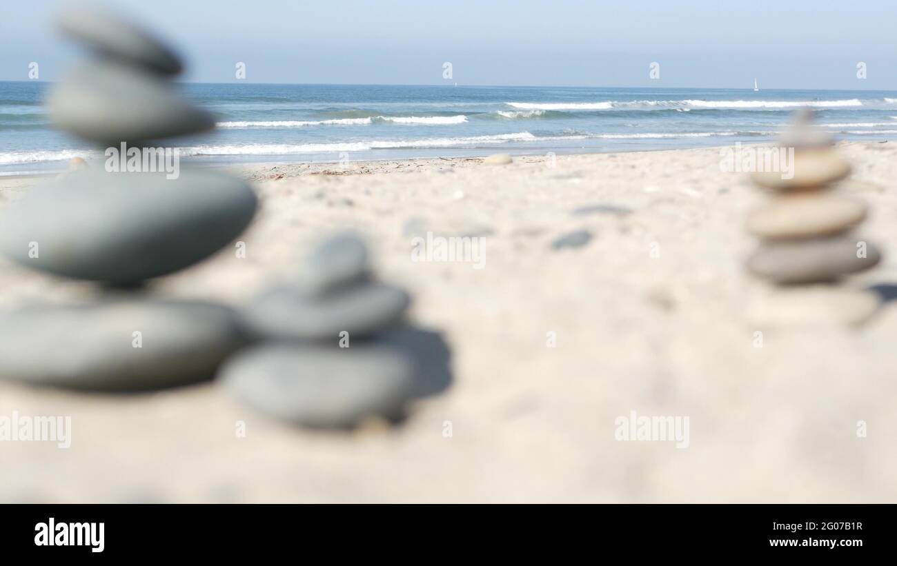 Rock balancing on ocean beach, stones stacking by sea water waves ...