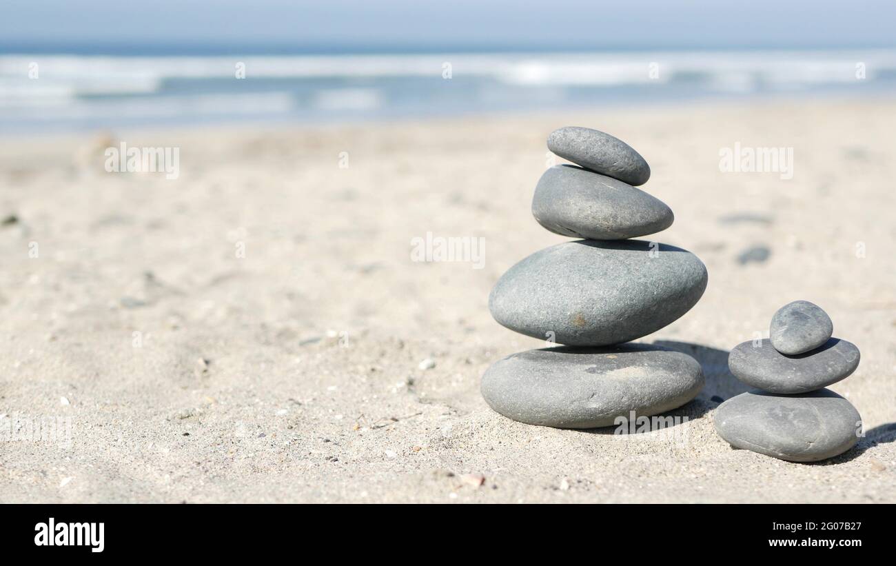 Rock balancing on ocean beach, stones stacking by sea water waves ...