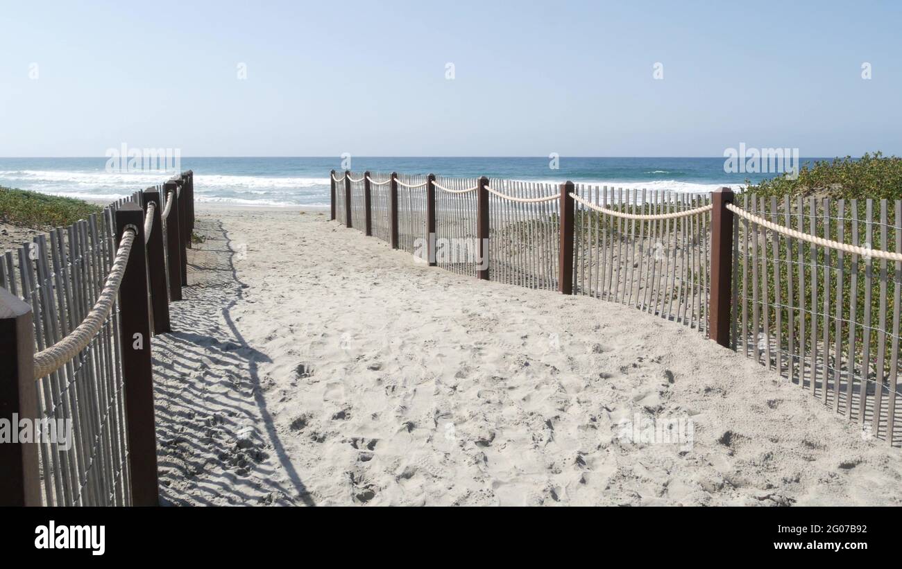 Pacific ocean coast, greenery and wooden picket fence on sea shore ...