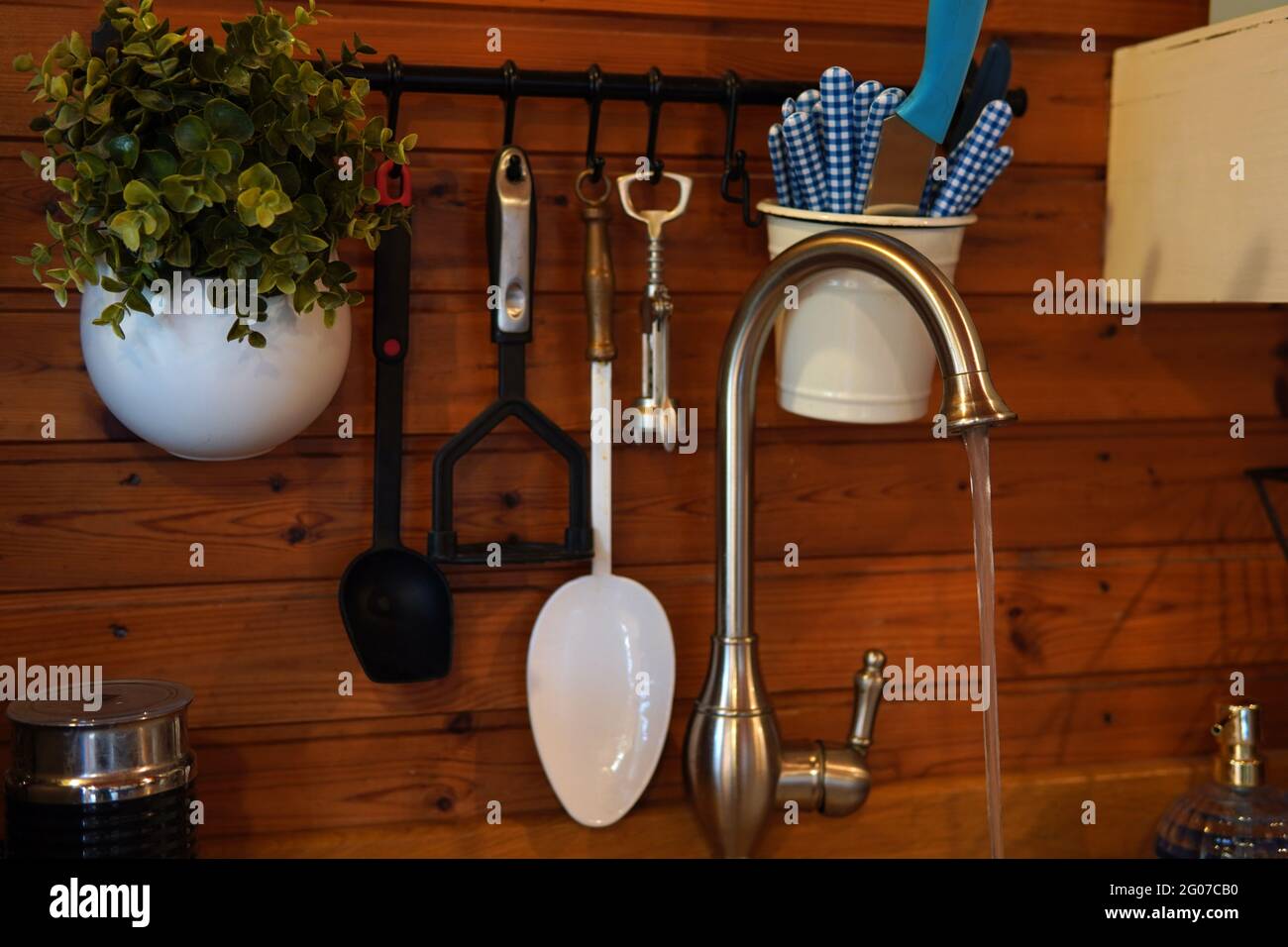 Kitchen interior with a metal faucet and different equipment hanging on ...