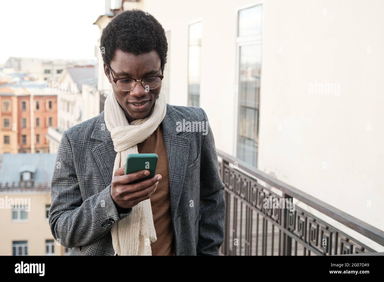 African man in coat reading a message on his mobile phone while ...