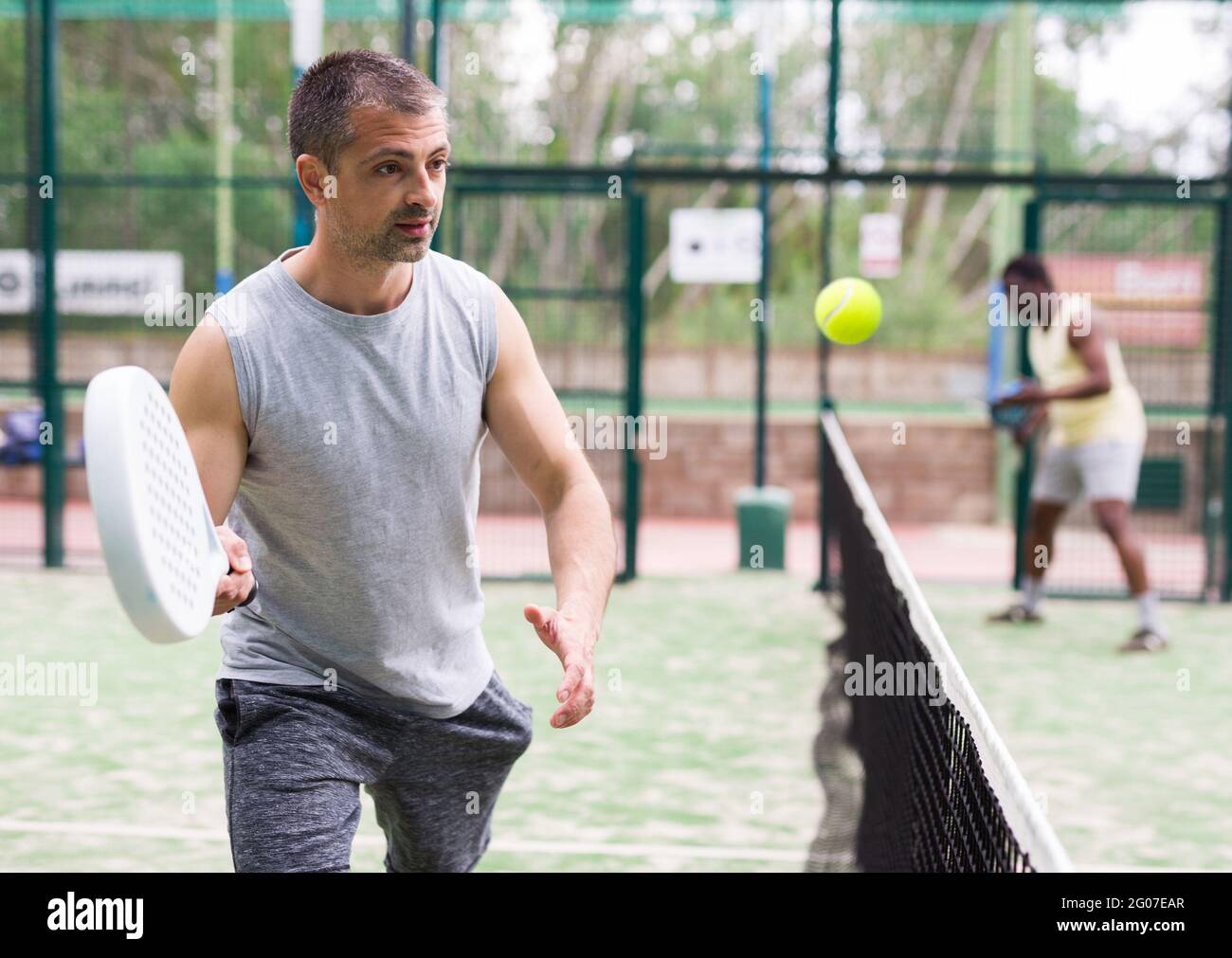 Male players playing padel in a padel court outdoor behind net Stock ...