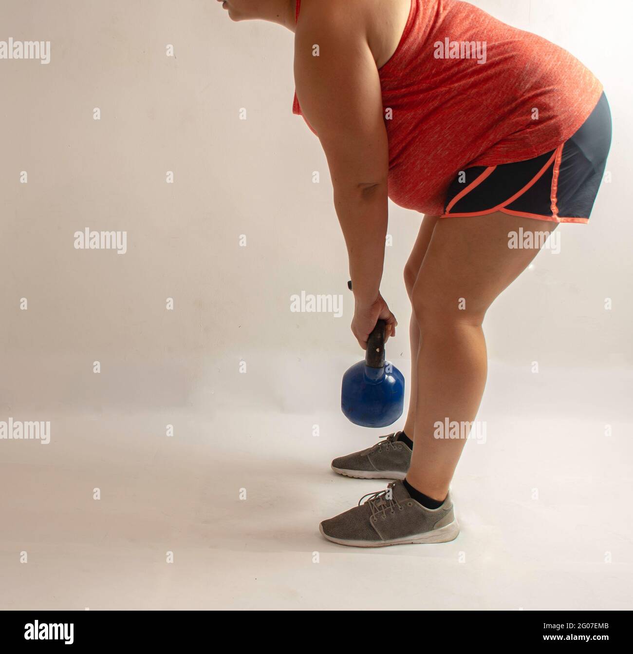 White woman performing deadlift with kettlebell on a white background ...