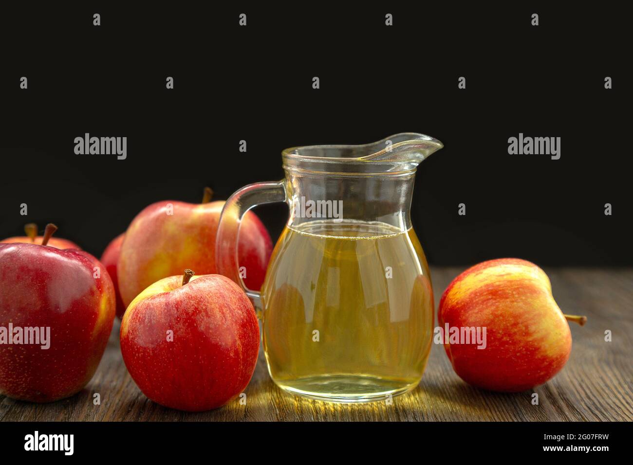 Hard apple cider in a glass jug and red ripe apples on a black ...