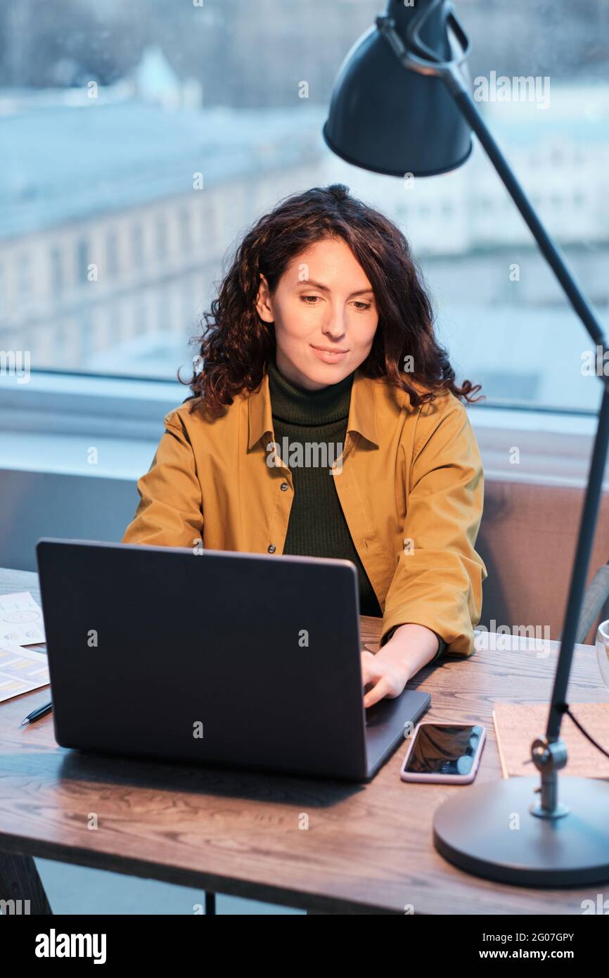 Pretty office worker using laptop computer in her work sitting at ...