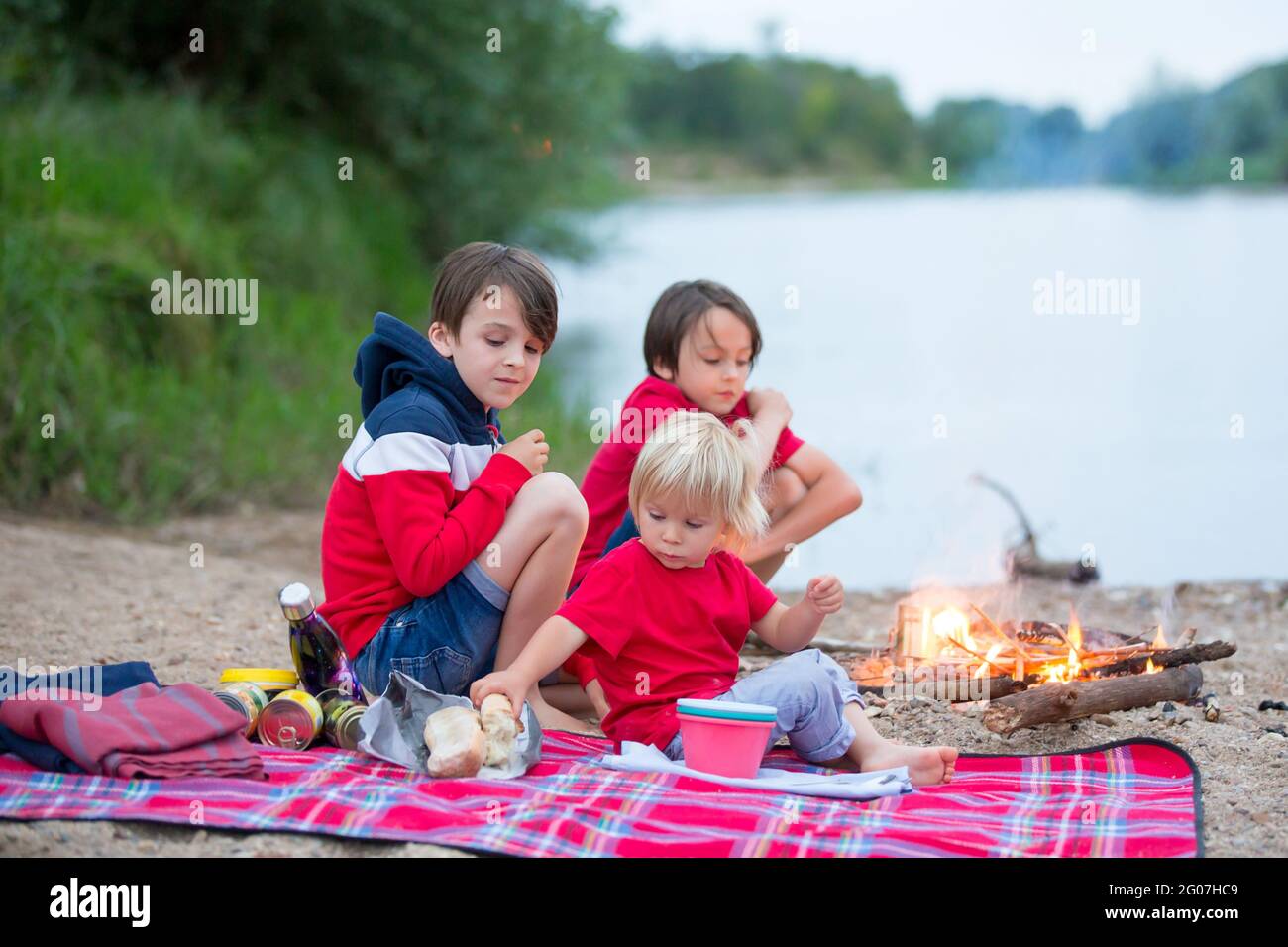 Family having picnic and campfire in the evening near river summertime ...