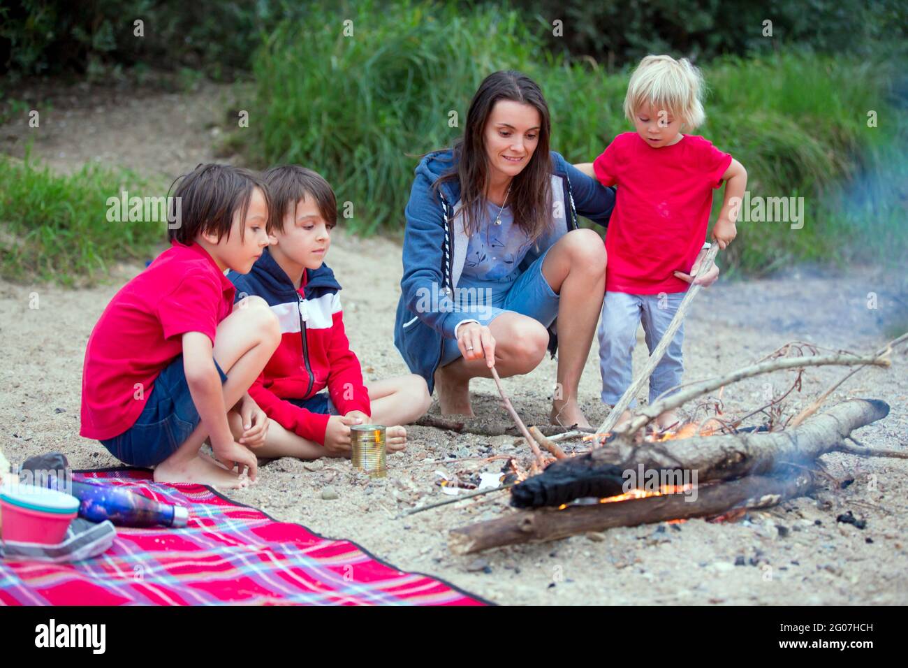Family having picnic and campfire in the evening near river summertime ...