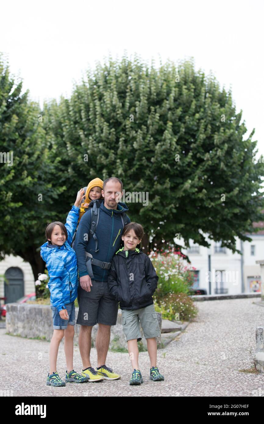Happy family, father and sons, walking in a little village in France ...