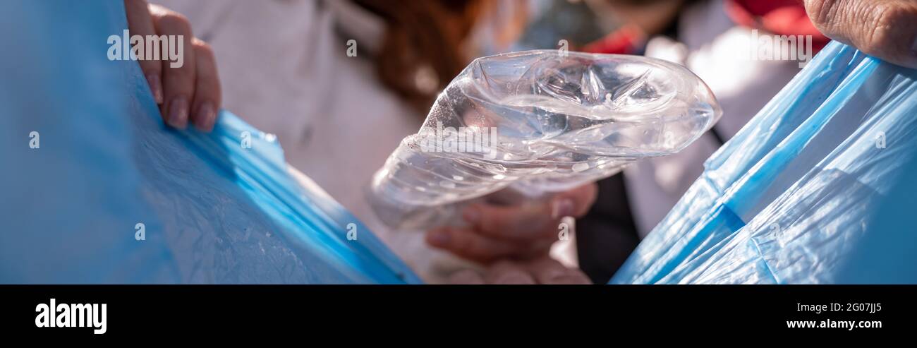plastic cup falling in trash bag near blurred volunteers, banner Stock ...