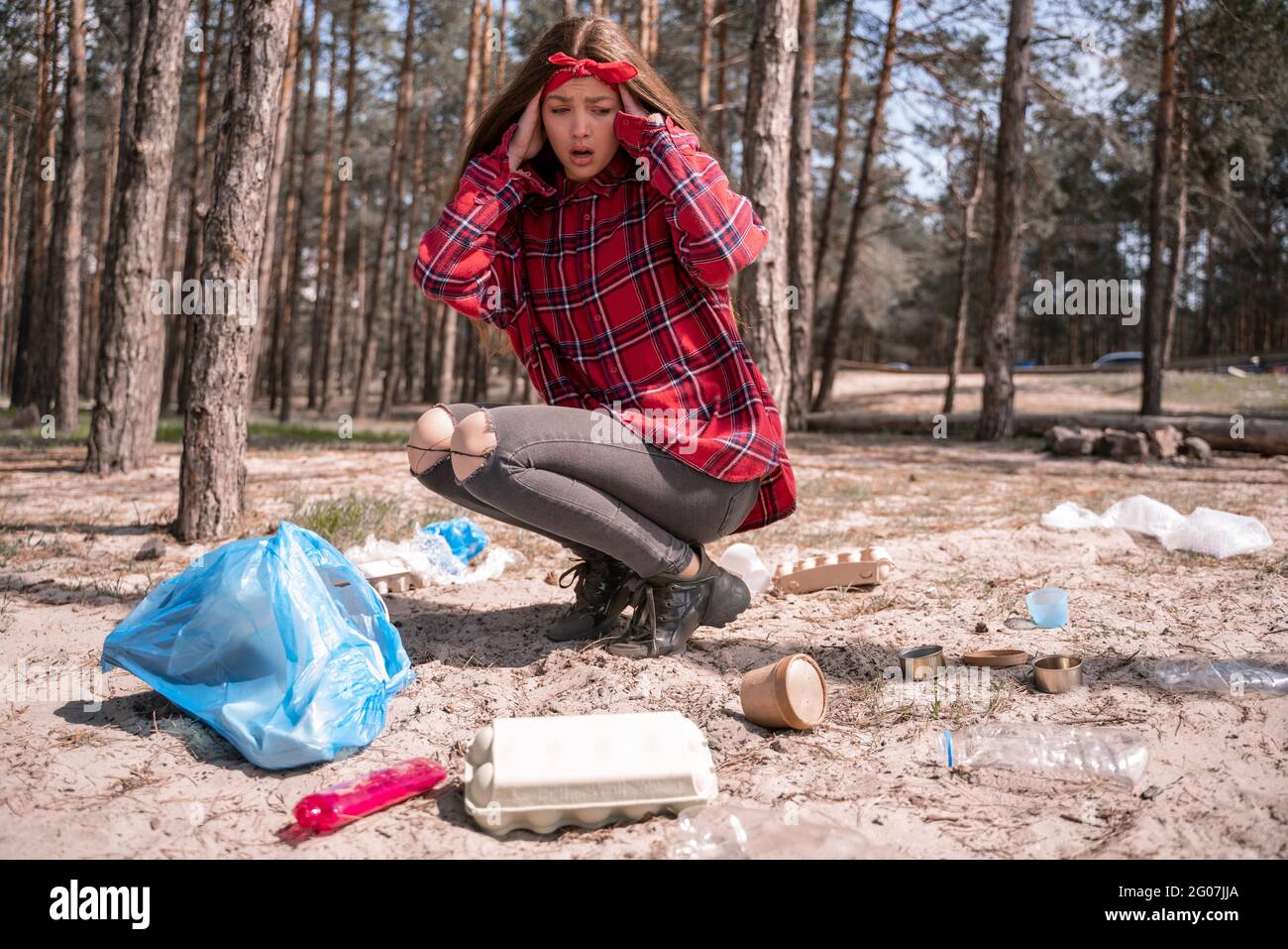 shocked young woman looking at garbage near trash bag in forest Stock ...