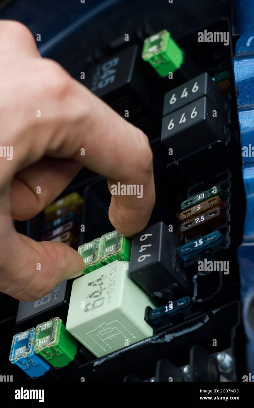 Man's hand replacing car fuses in a fuse box of a car. Macro focus ...