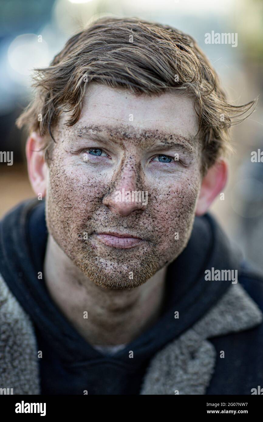 Close up of man covered by mud.A man's face covered in muddy spots ...