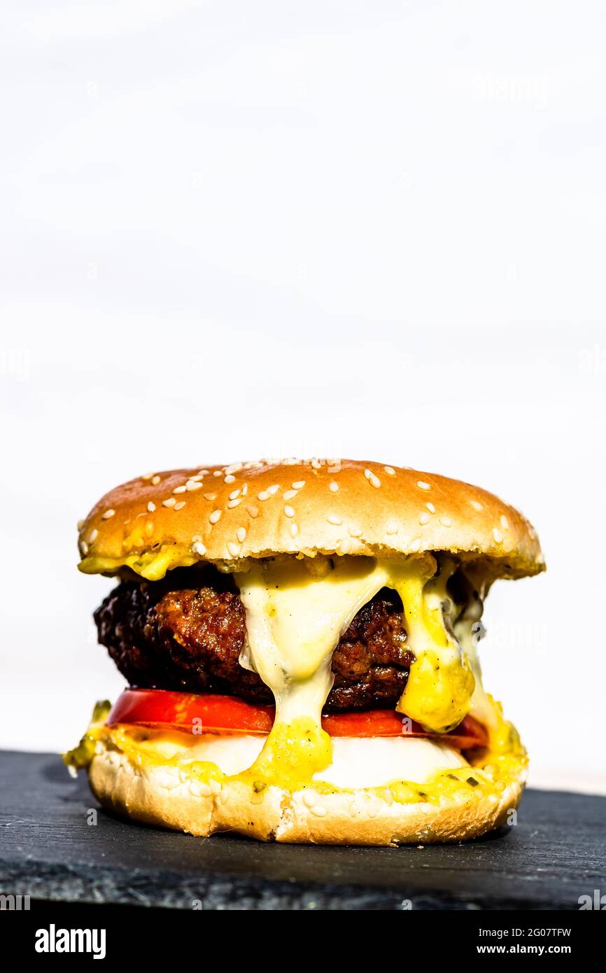 Vertical shot of a tasty beef cheeseburger with melted cheese isolated ...