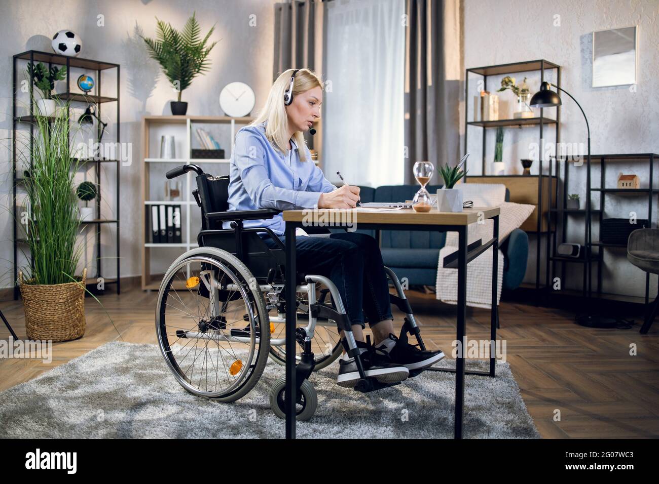 Side view of woman with disabilities taking notes during video ...