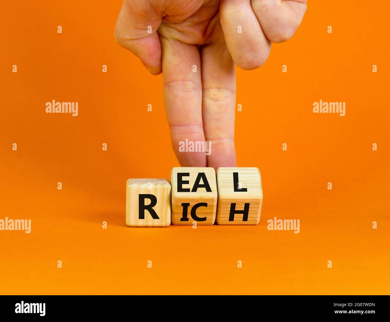 Real rich symbol. Businessman turns wooden cubes with words 'Real rich ...