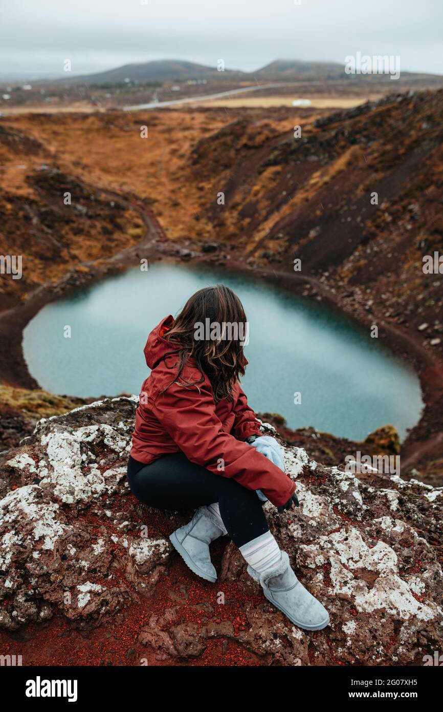 Low angle back view of anonymous female tourist standing on rock and ...