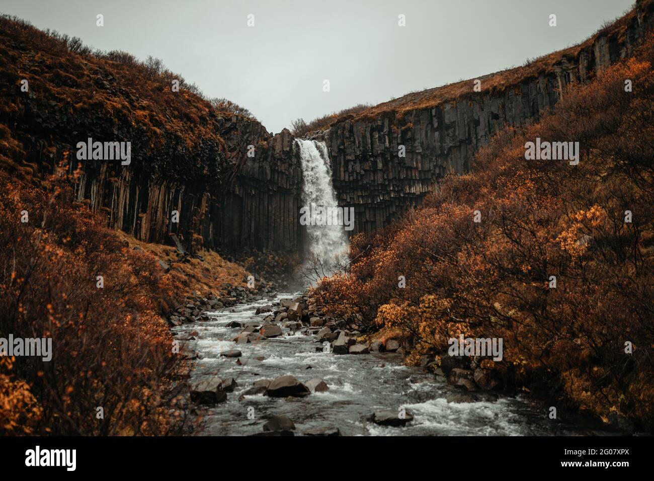 Picturesque view of cascade falling in river from cliff between dry ...