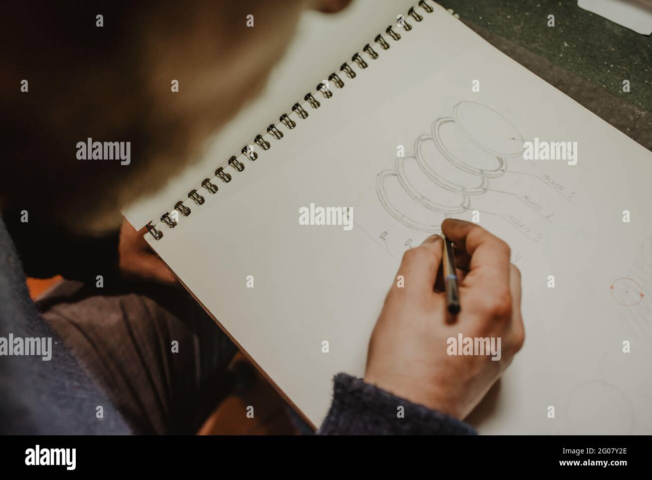 Crop goldsmith drawing ring sketch in open notepad while working in ...