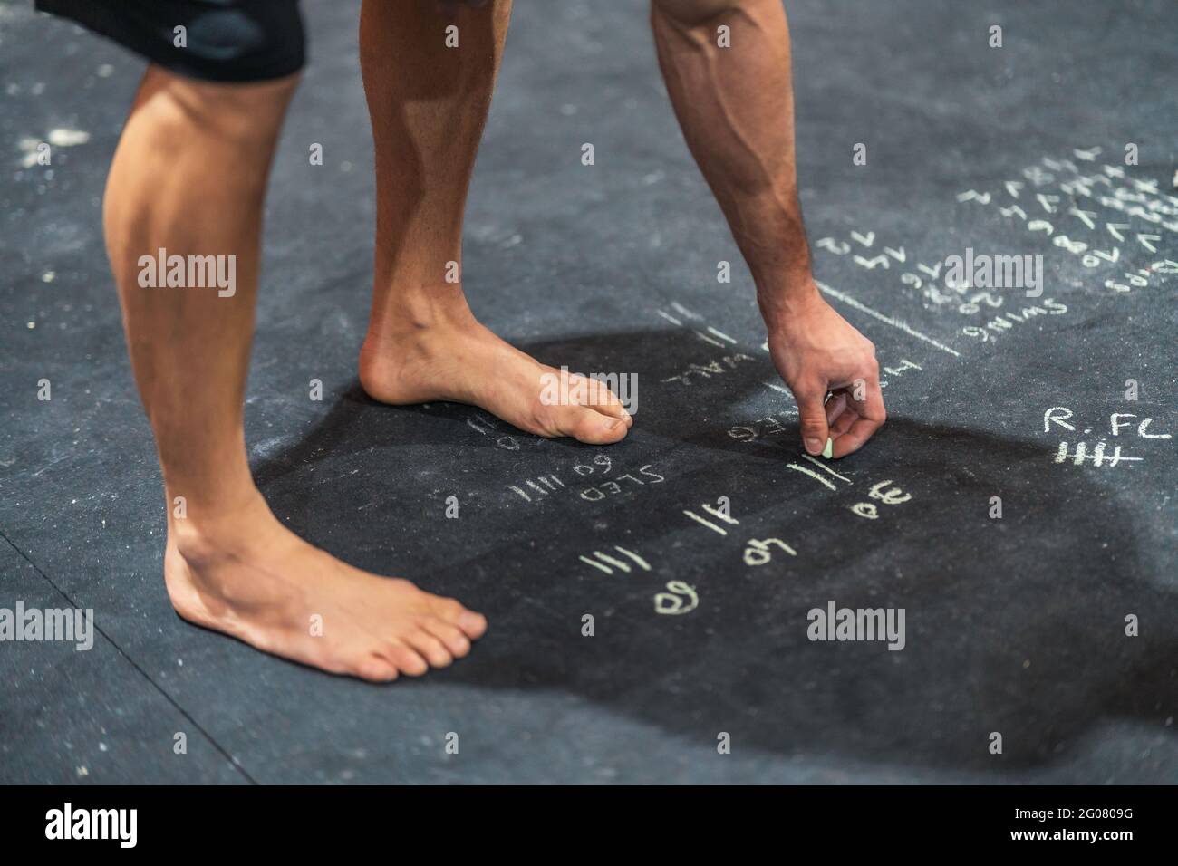 Unrecognizable barefoot sportsman making notes with chalk on floor ...