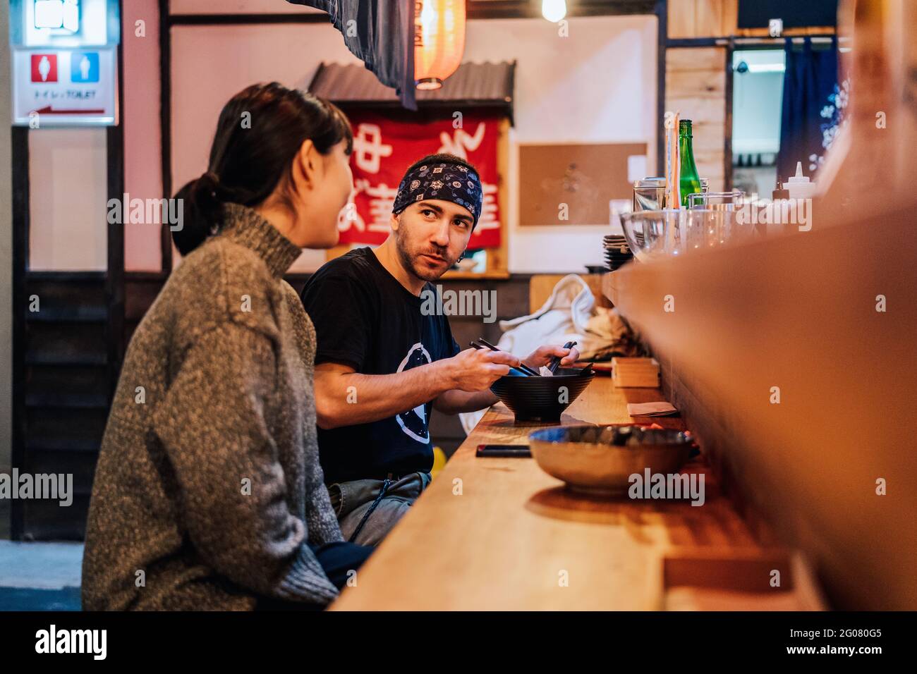 Side view of Woman and man communicating while eating Asian food at ...
