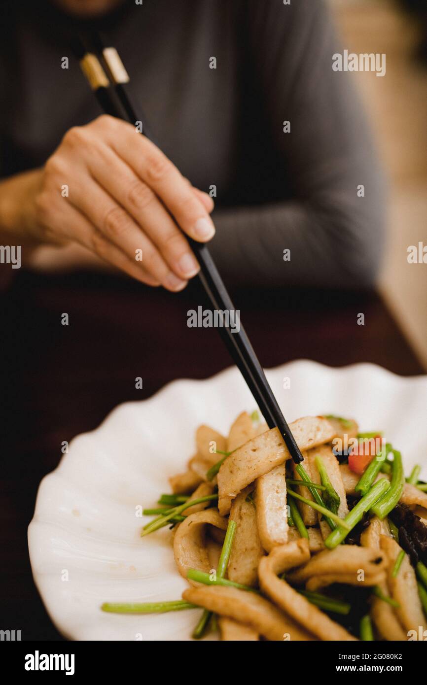 Female eating cooked delicious squid with vegetables with chopsticks in ...