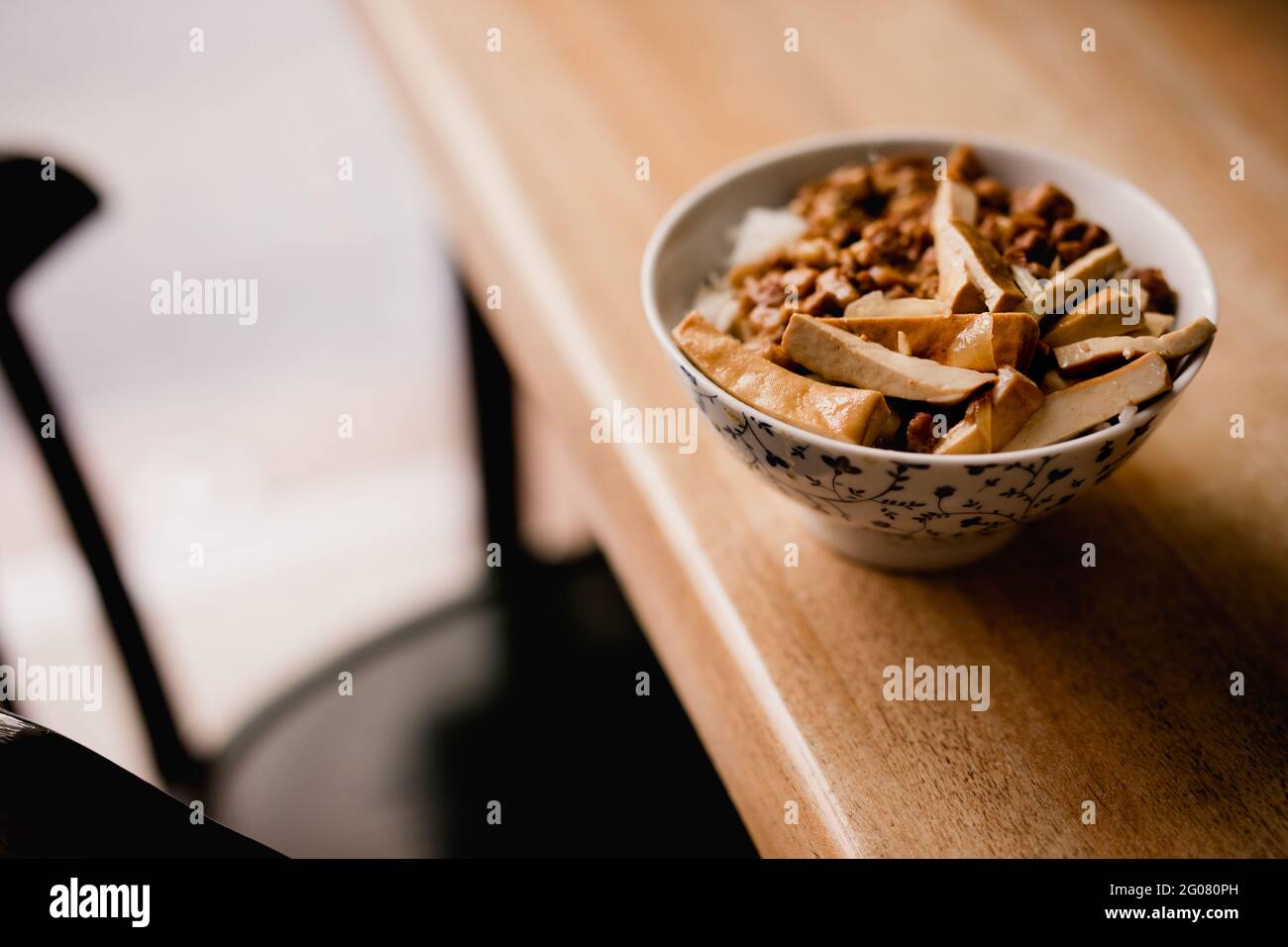 Ceramic bowl of yummy Lu Rou Fan dish with tofu placed on table in cafe ...