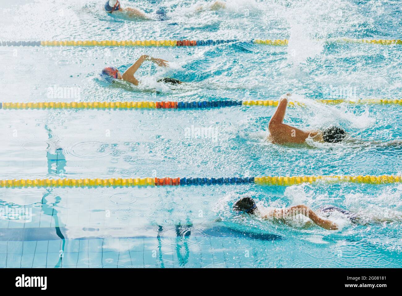From above side view of people swimming with splashes in pool with ...