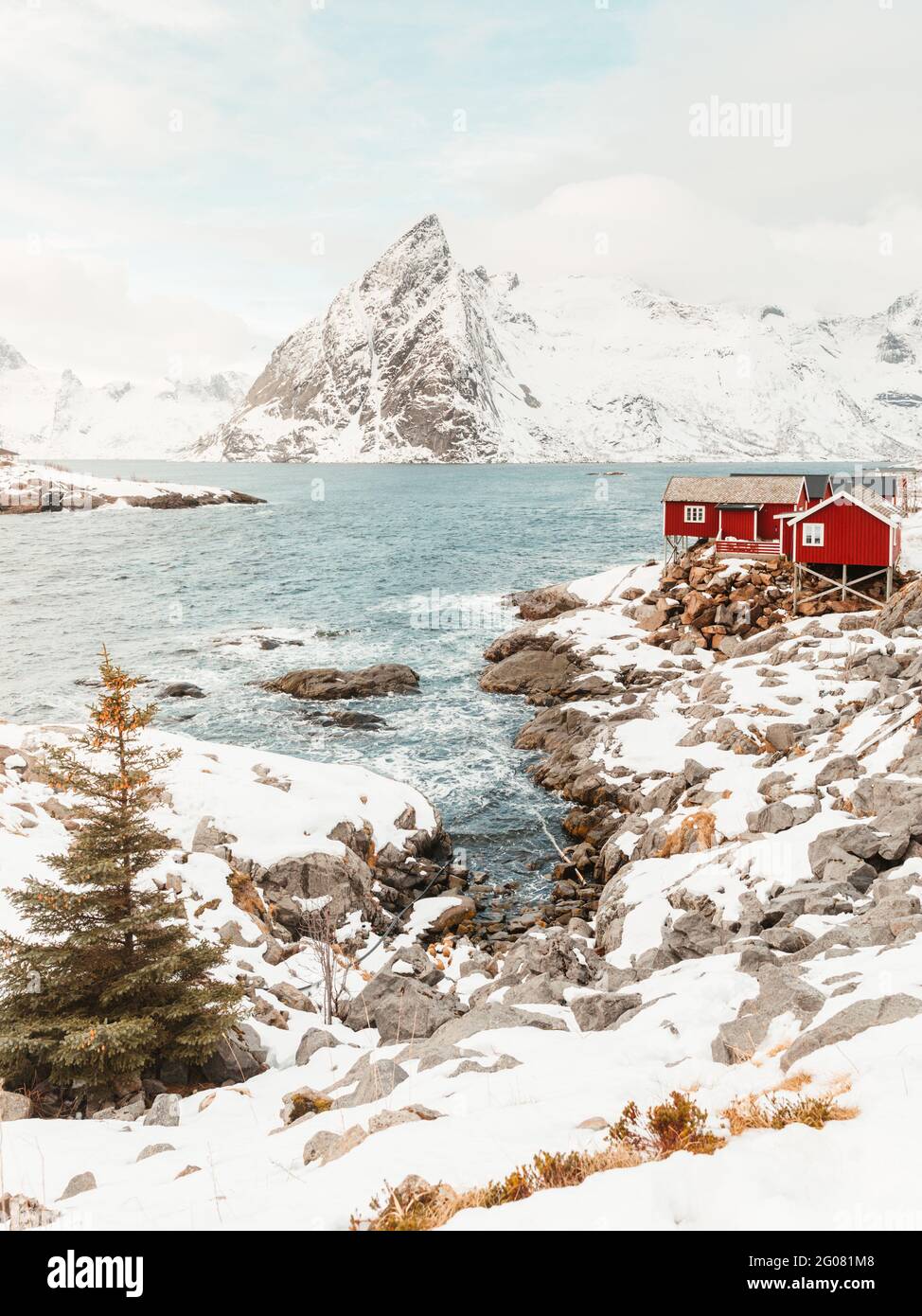 Red cabins located on mountain range snowy coast on Lofoten Islands ...