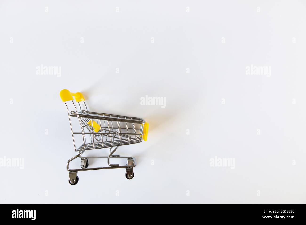 Small empty decorative shopping cart toy with yellow accents on a white ...